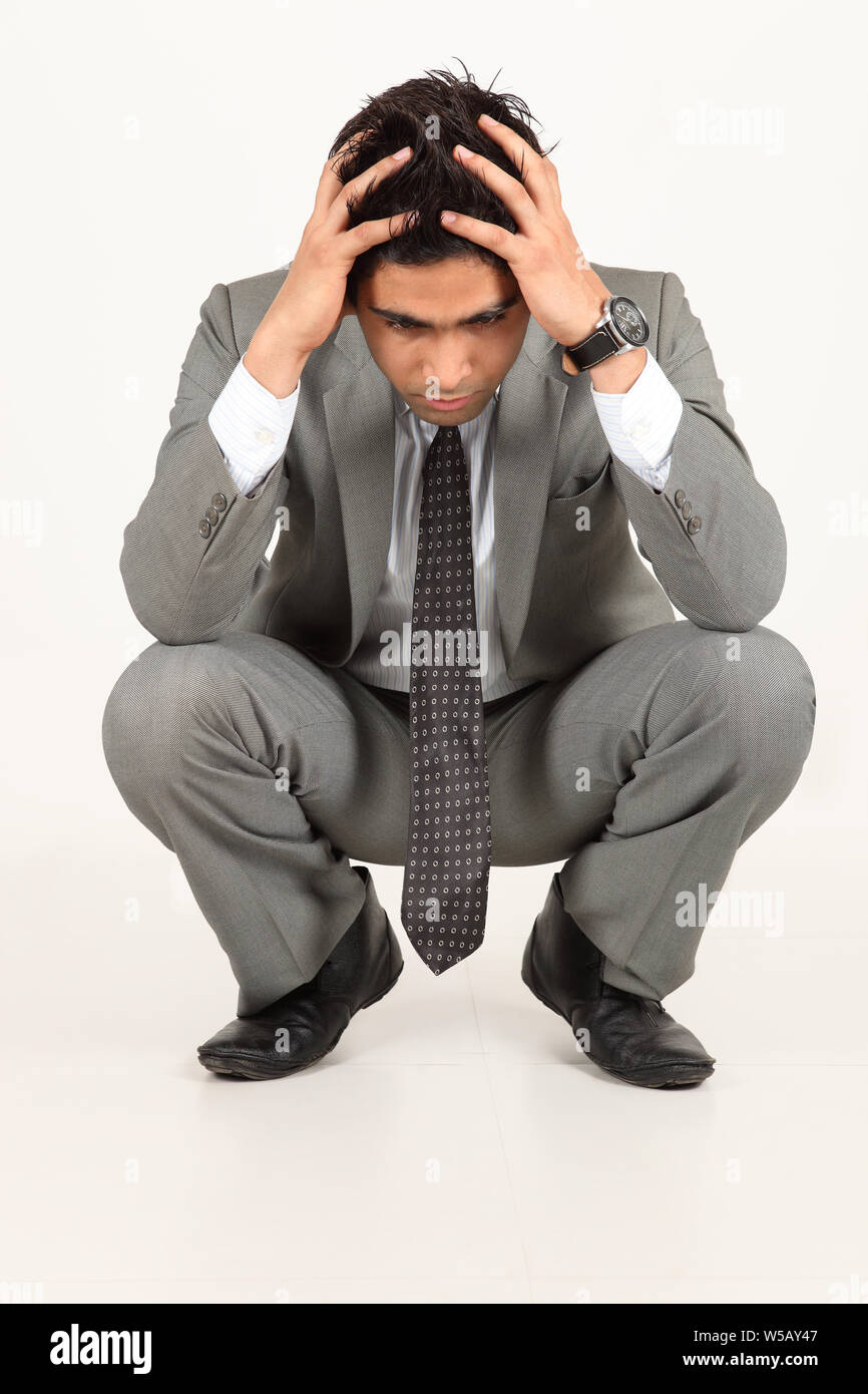 Indian businessman crouching with head in hands Stock Photo - Alamy