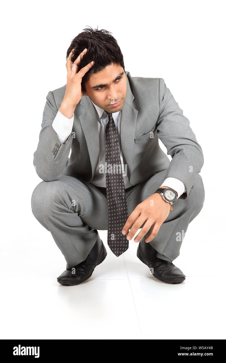 Businessman crouching with head in hands Stock Photo - Alamy