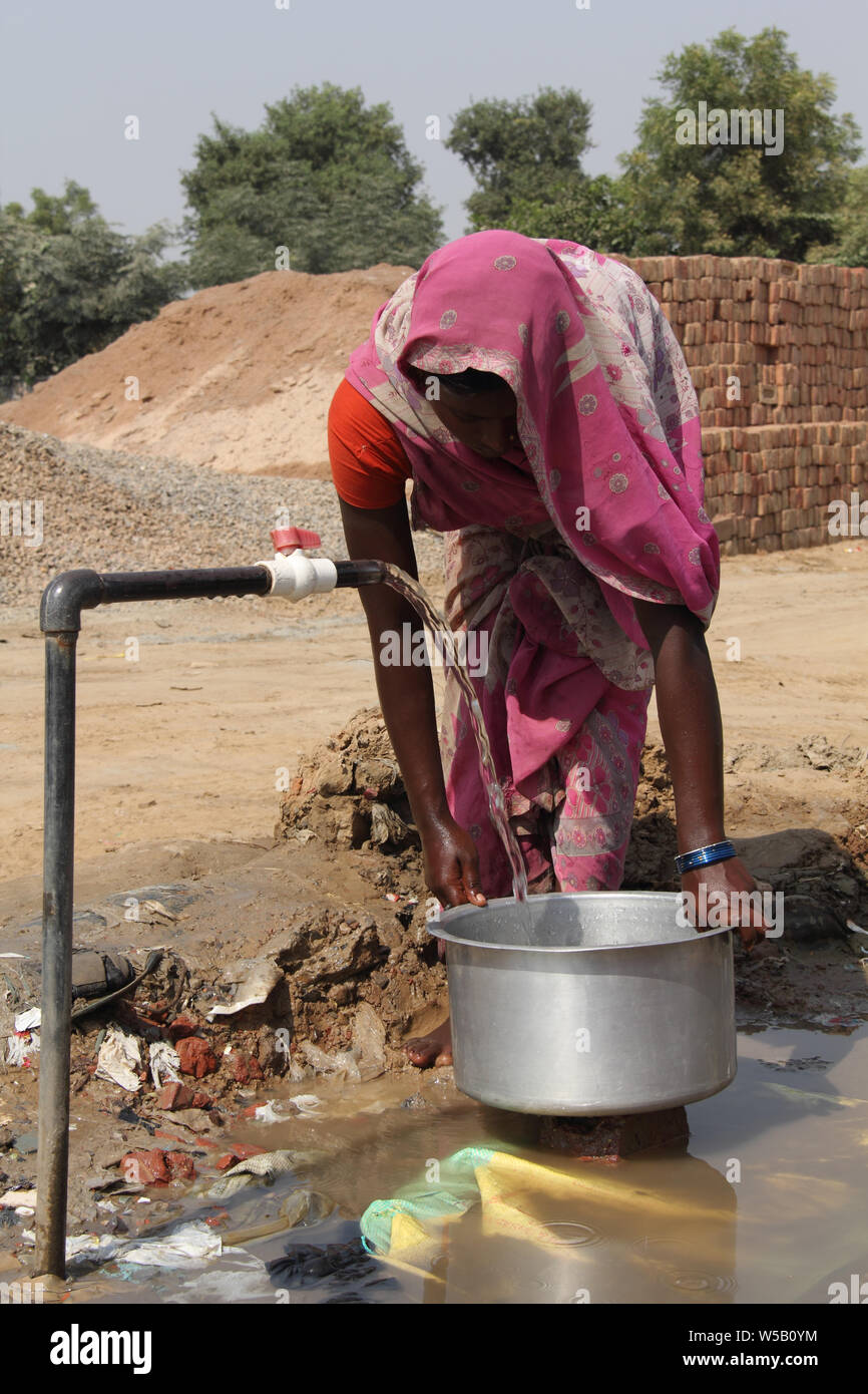 Woman collecting water from a water tap Stock Photo - Alamy