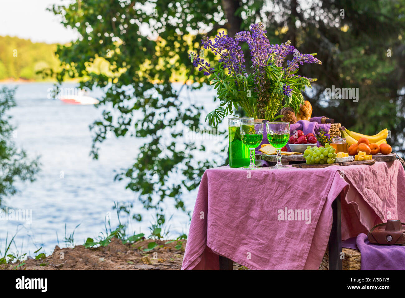 picnic near water at table with flowers in forest fruits and vegetables ...