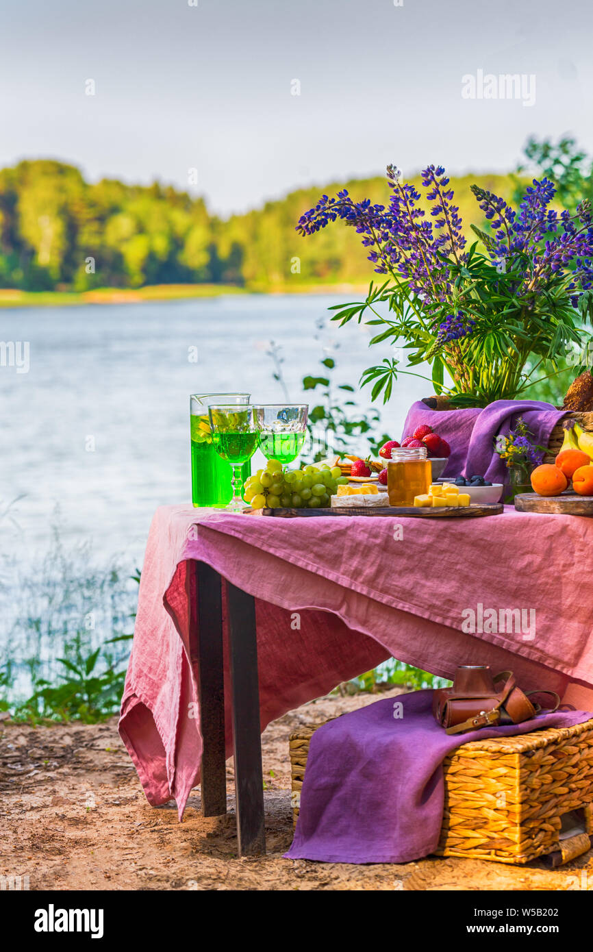picnic near water at table with flowers in forest fruits and vegetables ...