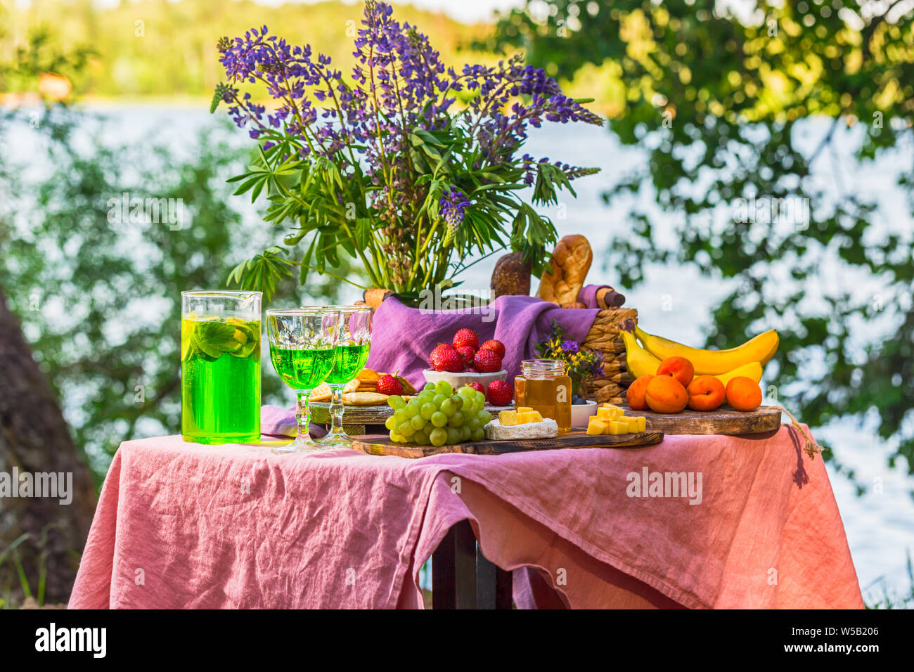picnic near water at table with flowers in forest fruits and vegetables ...