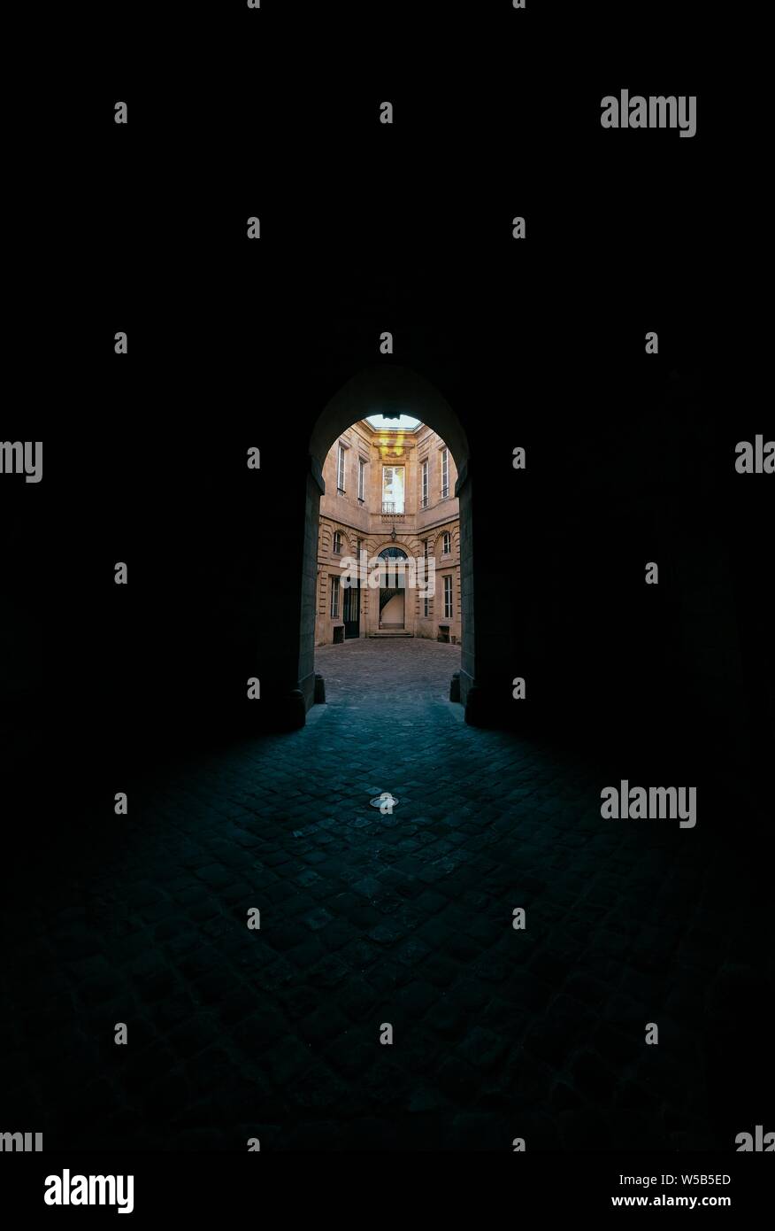 Dark hallway with arched doorway with a view of a concrete building ...