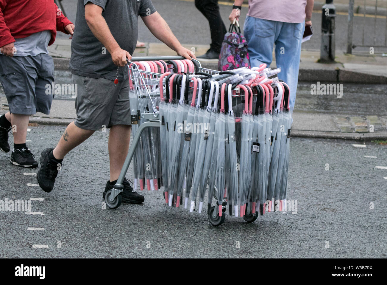 An umbrella salesman sells brollies from his portable trading stall in ...