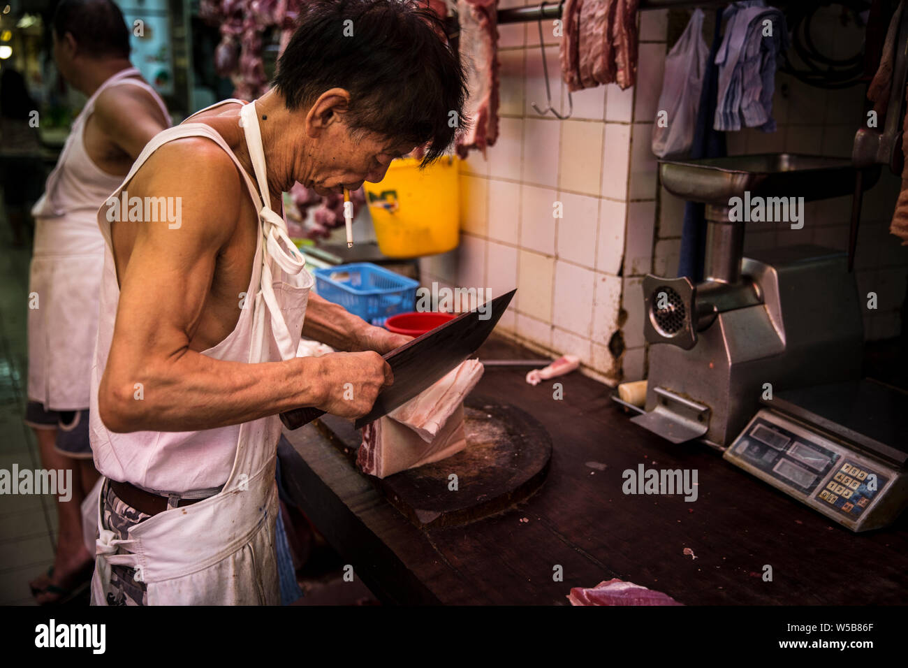 Butcher smoking and cutting meat at Fa Yuen market. Hong Kong Stock ...