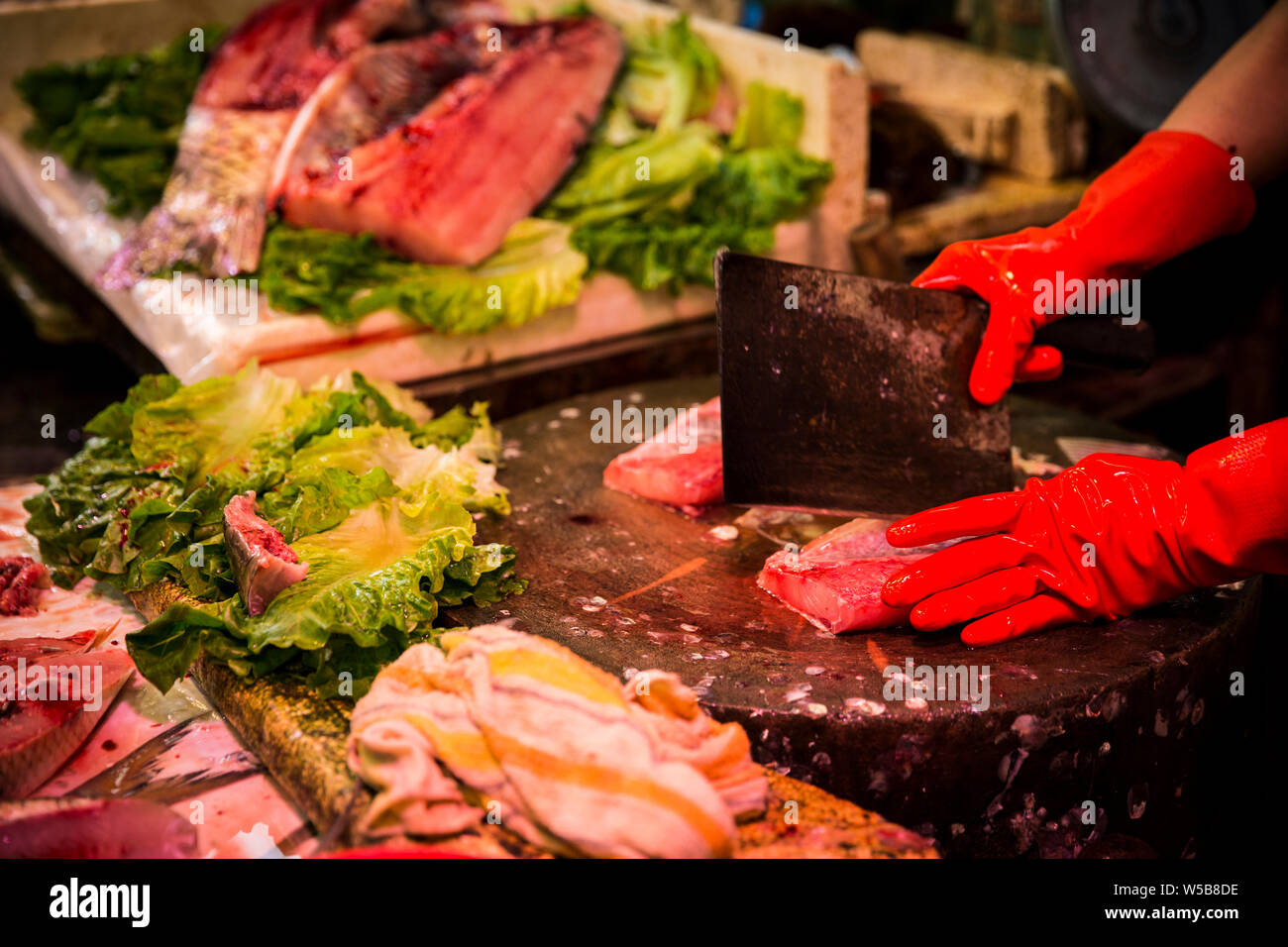 Fishmonger cutting a piece of fresh fish at Fa Yuen market. Hong Kong ...