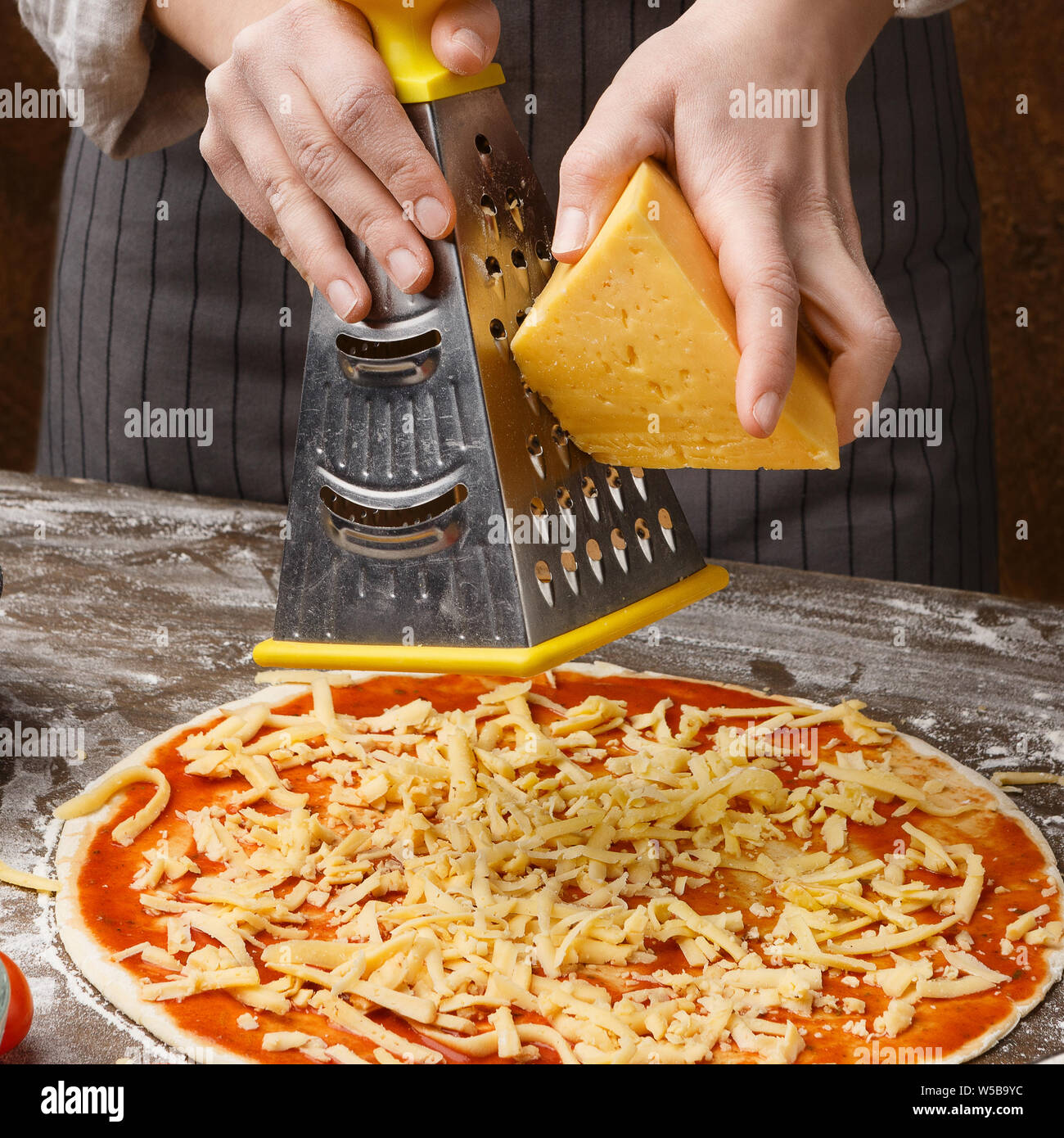 Female chef rubbing cheese on grater at pizzeria Stock Photo - Alamy