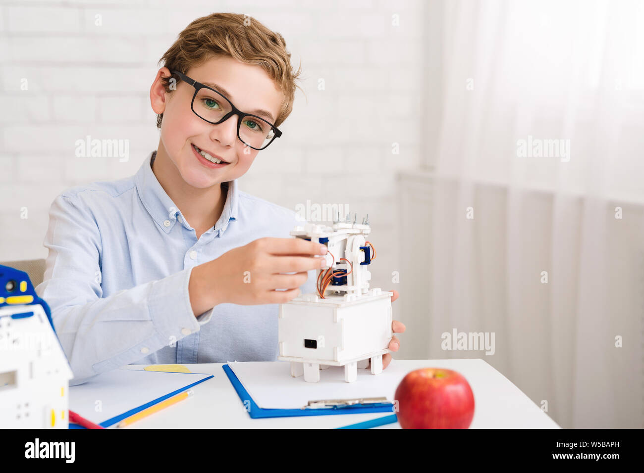 Happy boy constructing electric robot and looking at camera Stock Photo ...