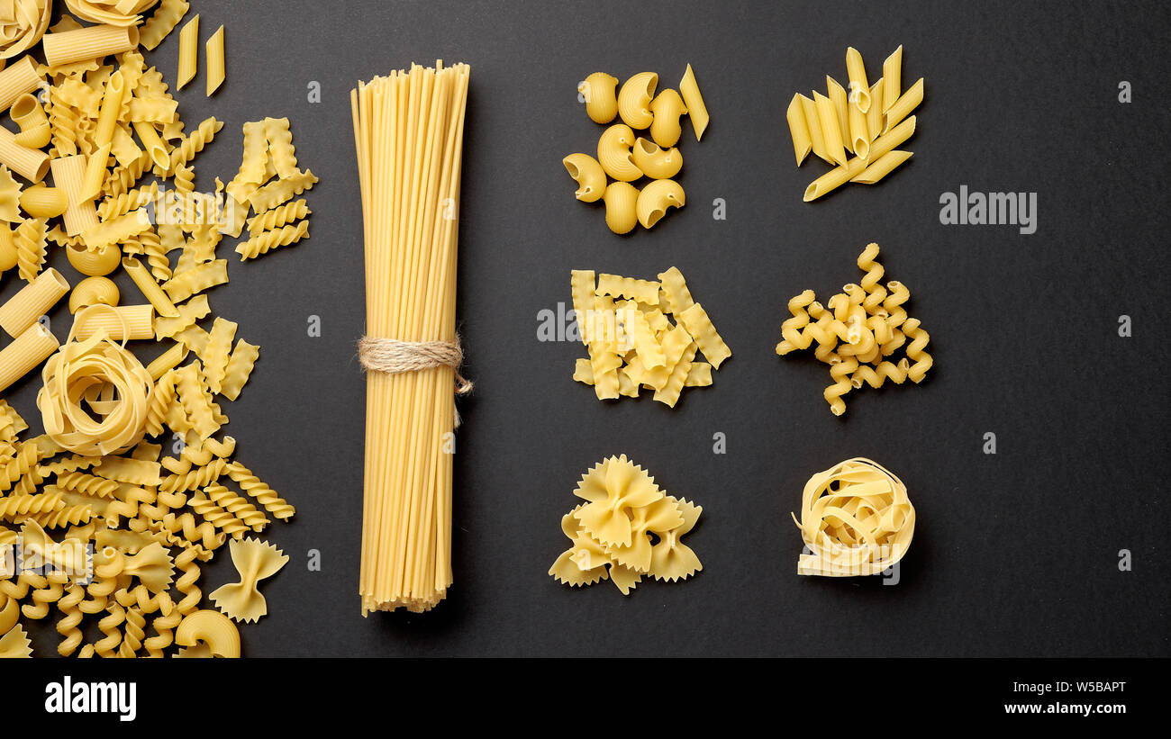 Assorted types of pasta on black background. Top view. Various forms of ...