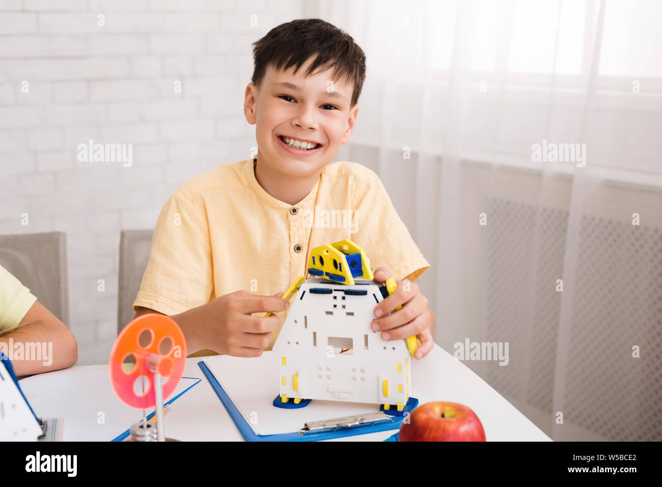 Smart boy constructing robot and smiling to camera Stock Photo - Alamy