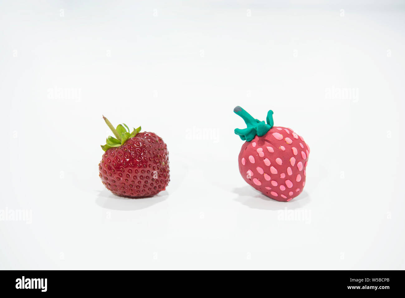 Comparison of two strawberries - Real and Fake Stock Photo - Alamy