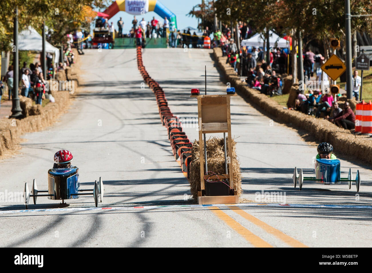 Two competitors cross the finish line in their soap box derby vehicles ...