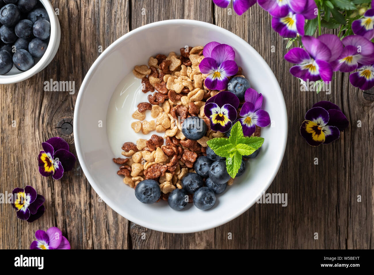 Breakfast cereals with yogurt, blueberries and edible pansy flowers ...