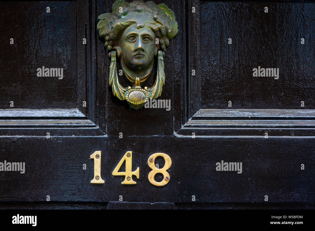 House number 148 on a black wooden front door with a door knocker in ...