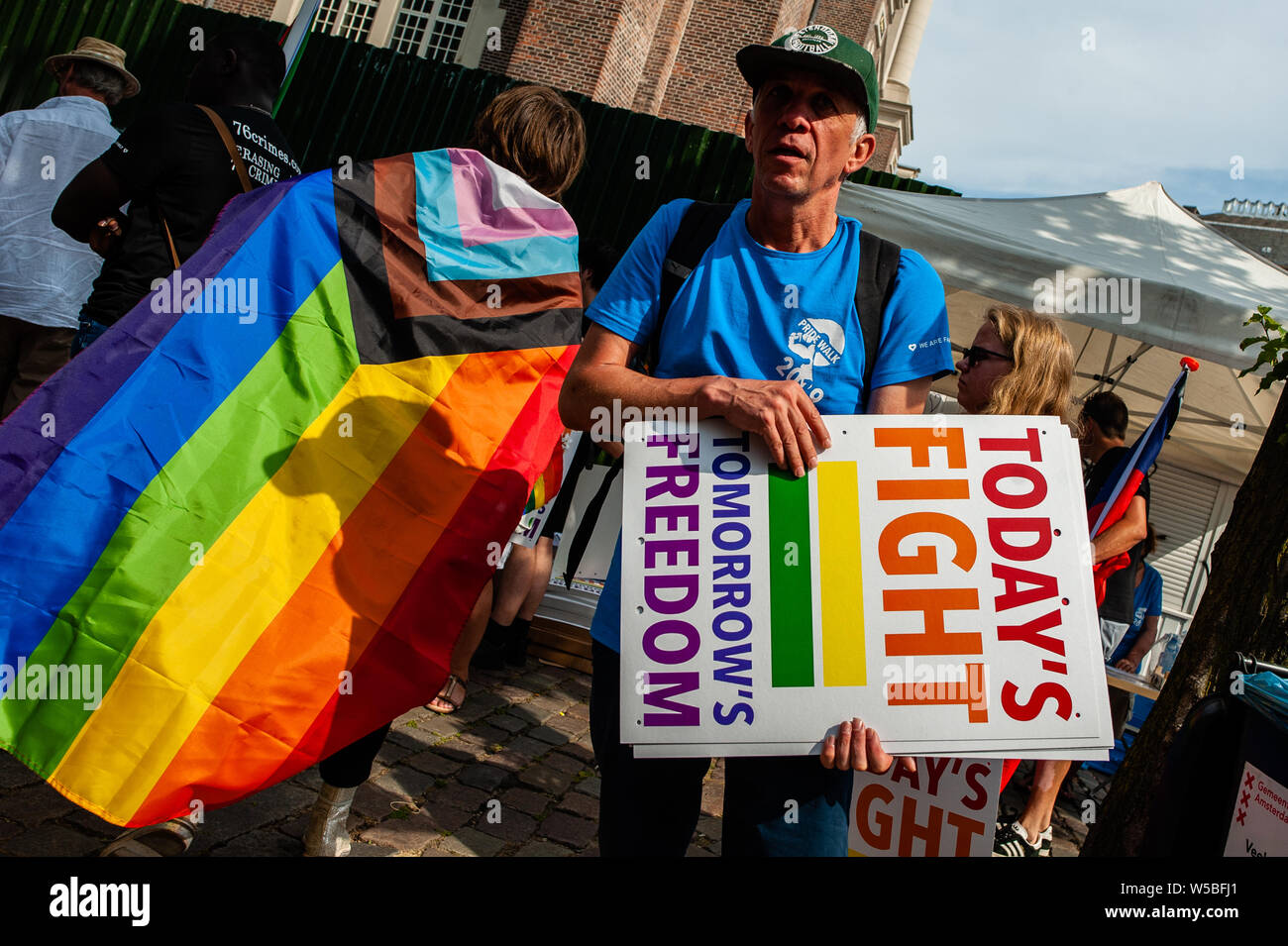 A man holds placards before the walk.Because of the Stonewall 50th ...