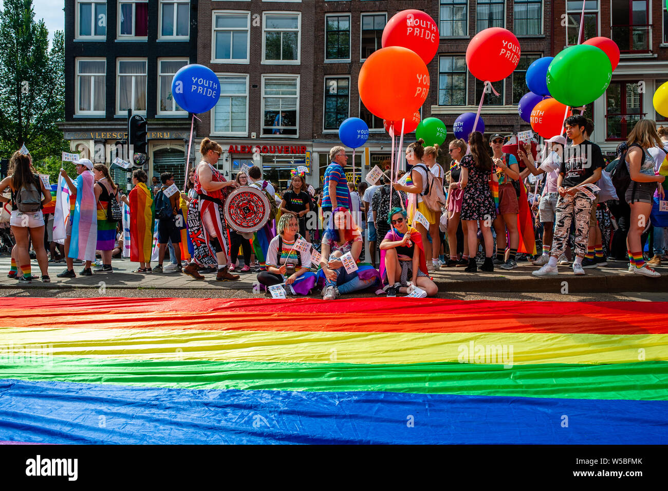 Activists seat on the ground next to a huge rainbow flag during the ...