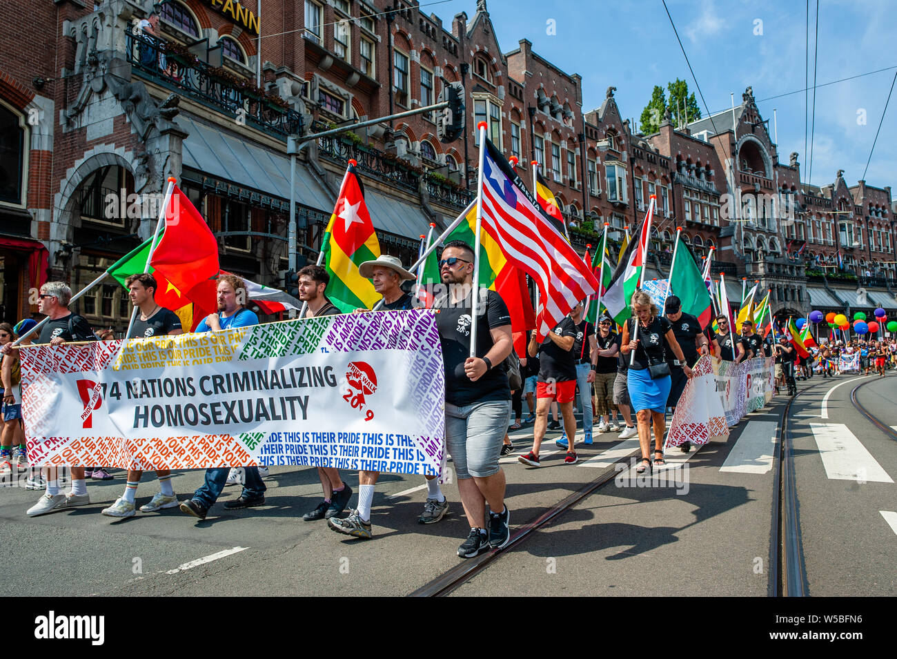 Participants walk with a banner while holding flags.Because of the ...