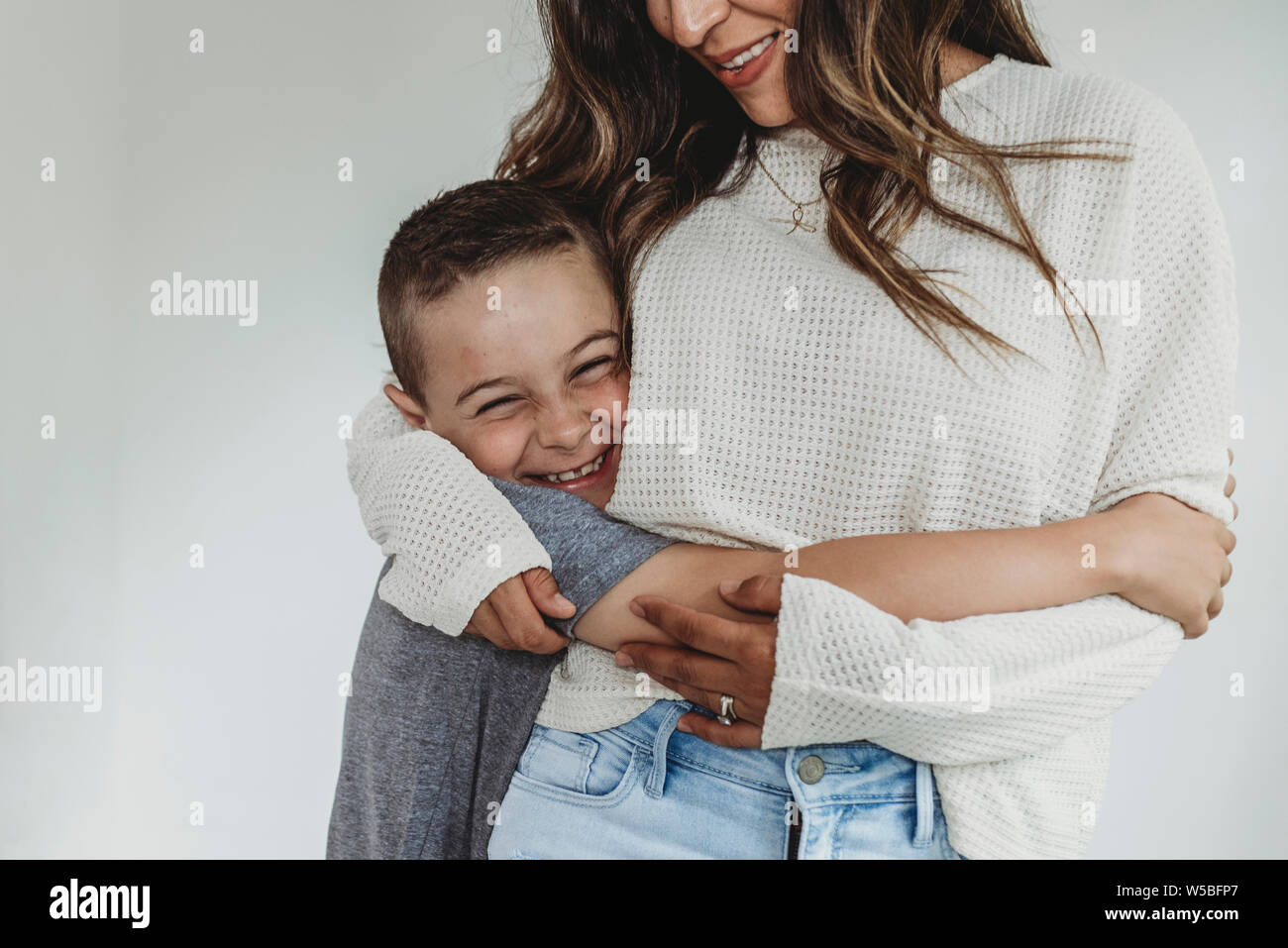 Close up view of son being hugged by mother and laughing in studio ...