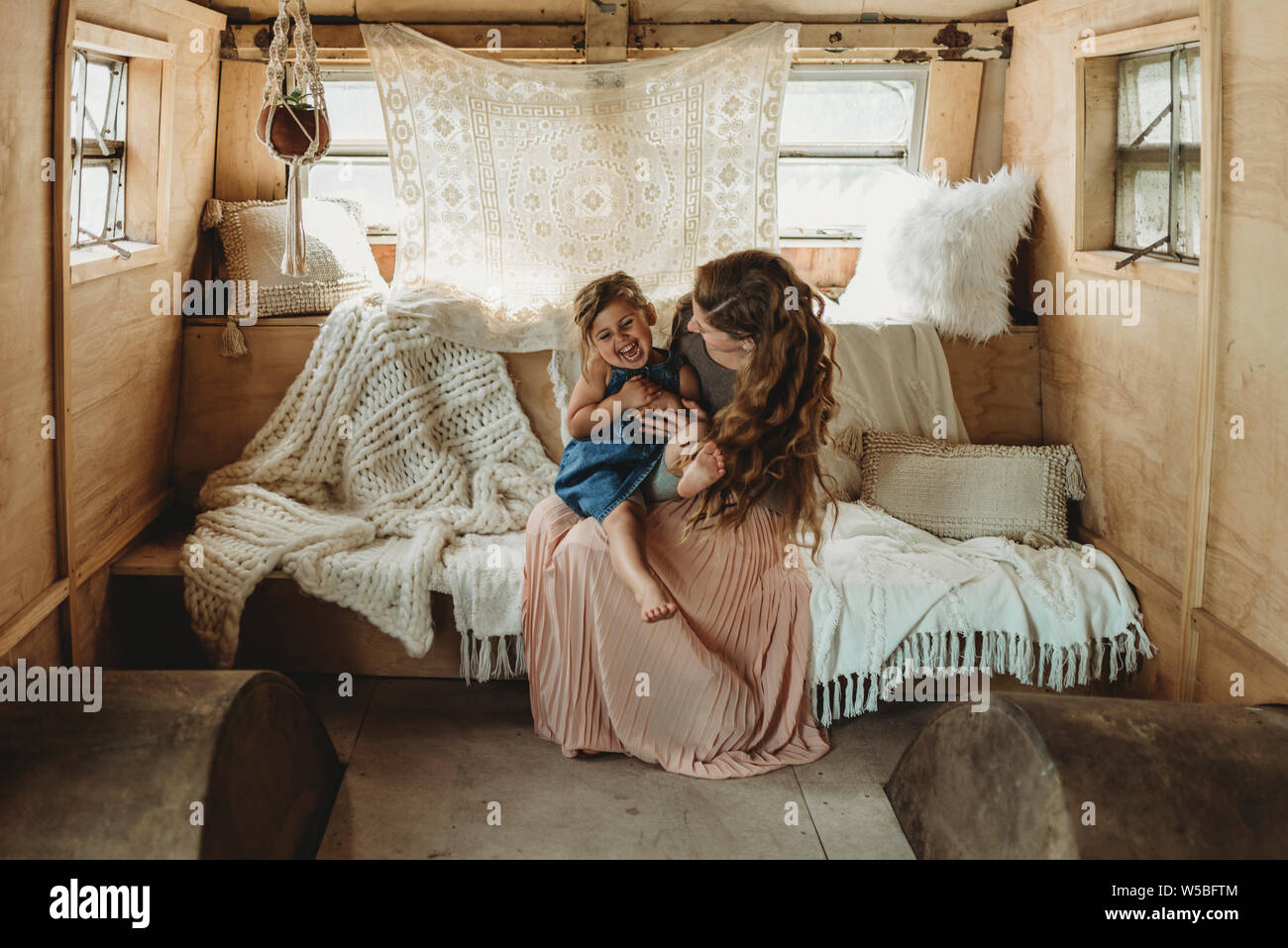 Mother and daughter cuddling and laughing in boho studio setup Stock ...