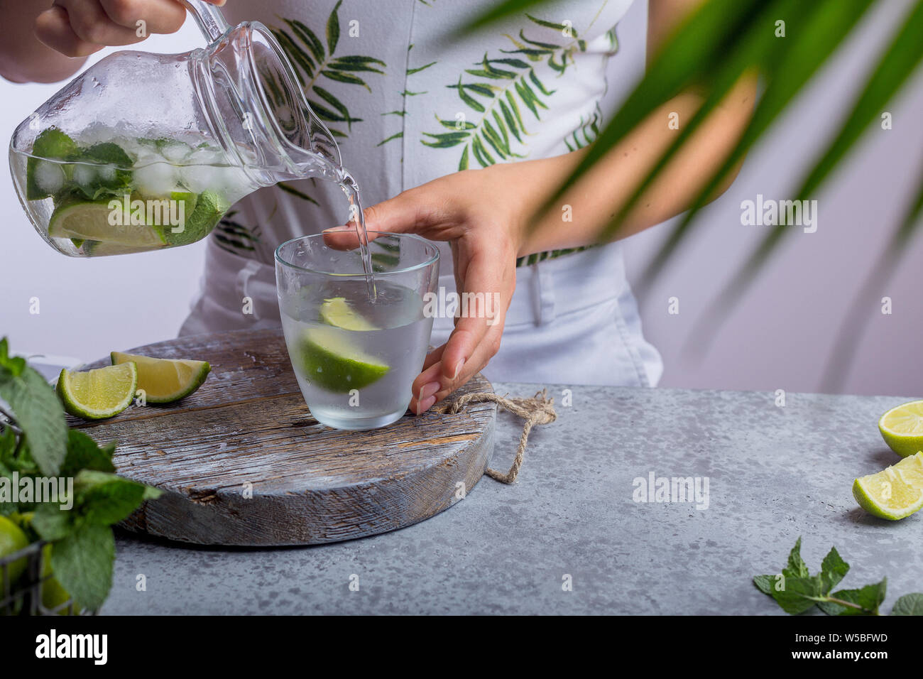 Young woman pouring fresh lemonade from jug into glass Stock Photo - Alamy