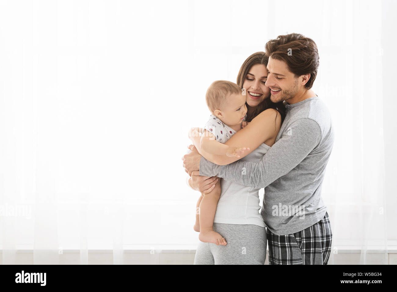 Loving parents cuddling with little baby son at window Stock Photo - Alamy