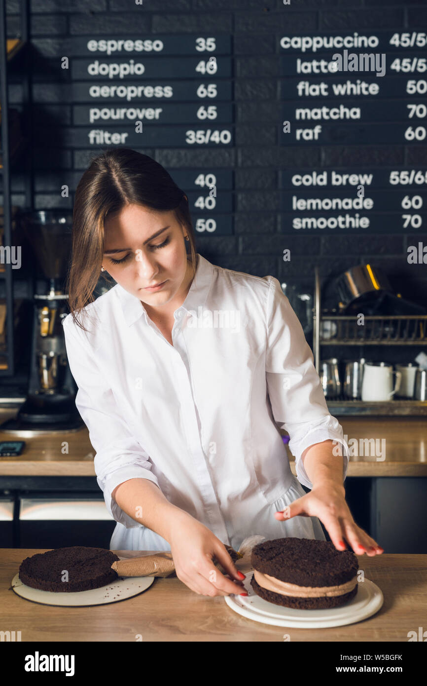 Young woman in white shirt bake a chocolate cake in cafeteria Stock ...