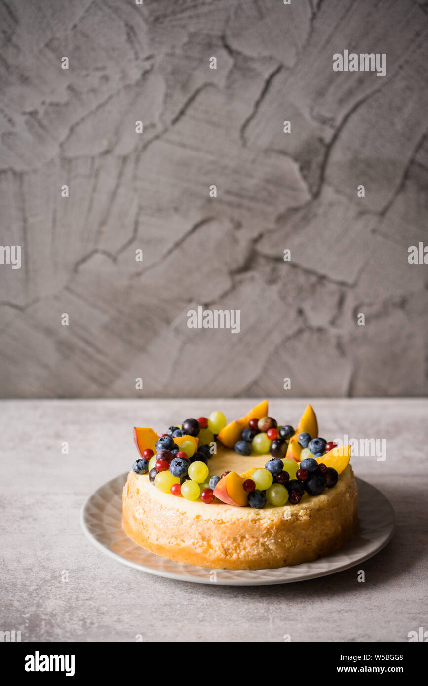 Cheesecake decorated by fruits and berries in front of concrete backgr ...