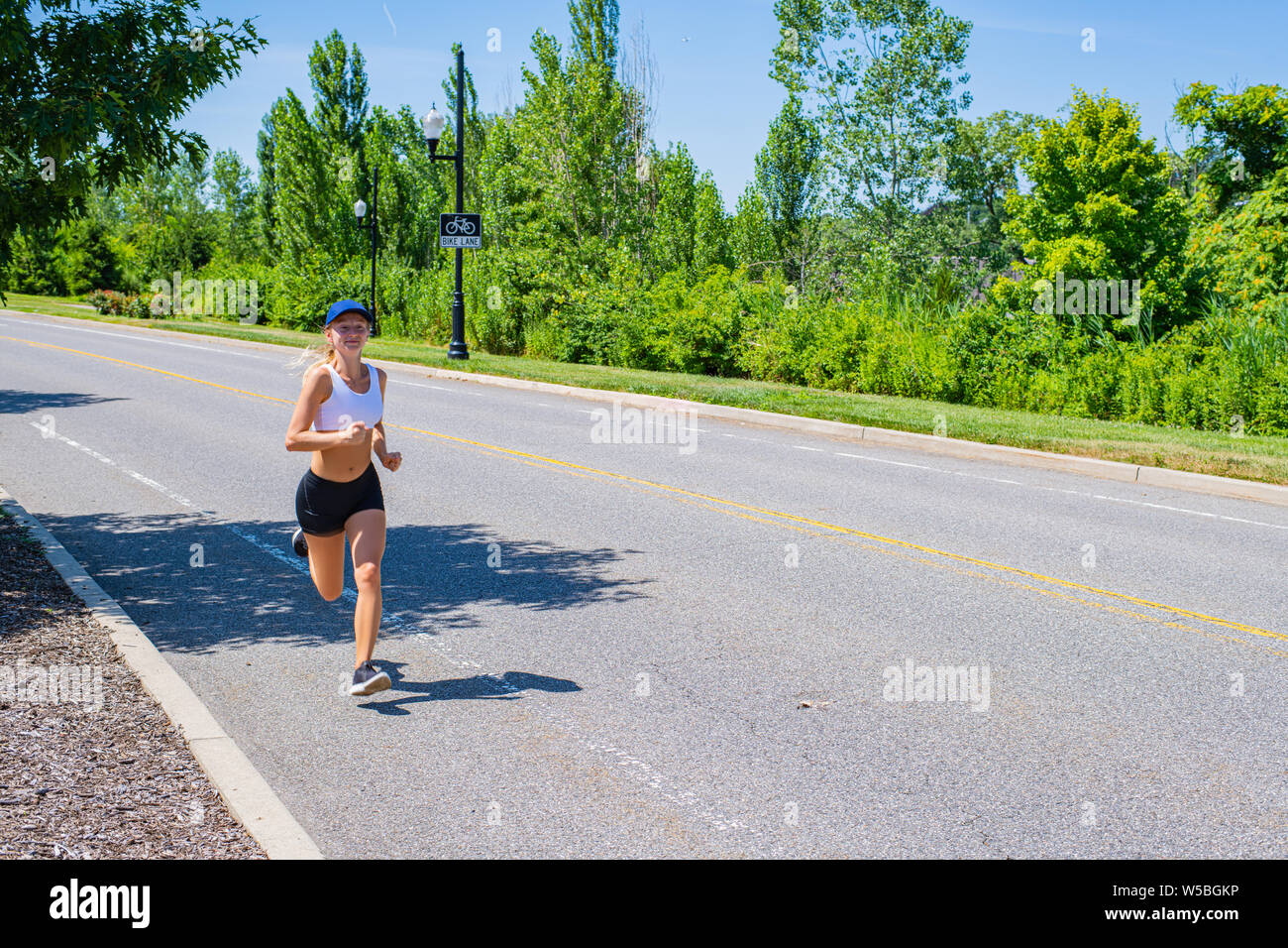 Sporty young woman in sportswear trail running on the road. Beautiful ...