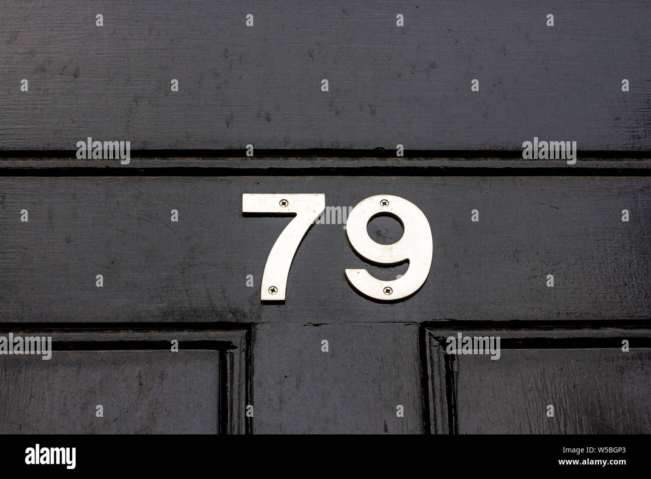 House number 79 in silver metal digits on a black wooden front door ...