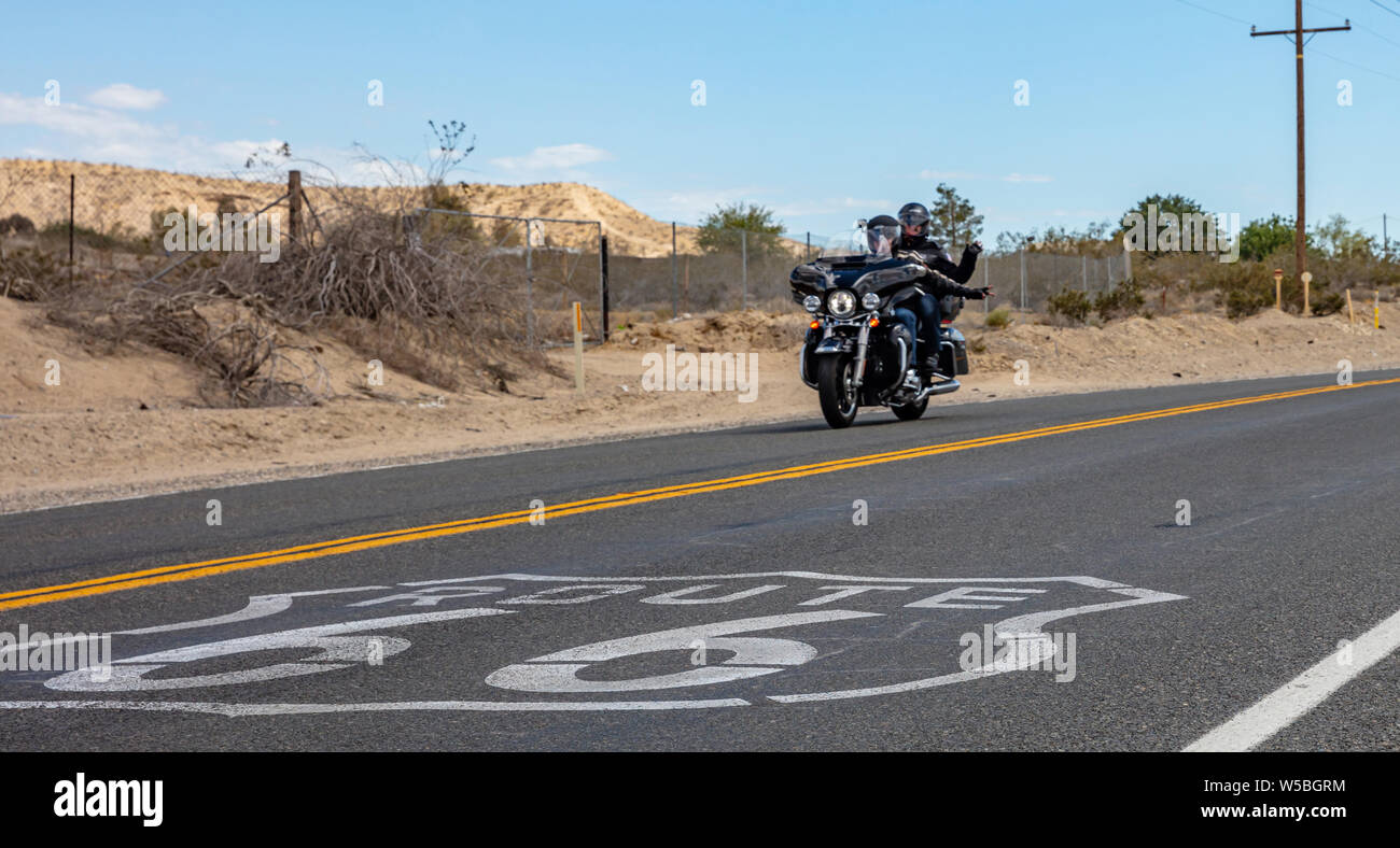 Route 66 and motorcycle. Young couple bikers waving, riding a moto in a ...