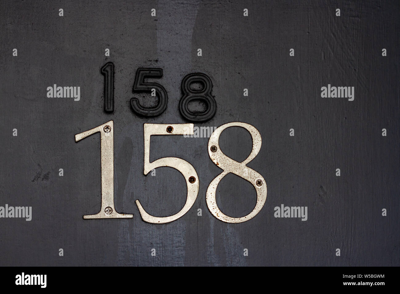 House number 158 written twice on a black door Stock Photo - Alamy