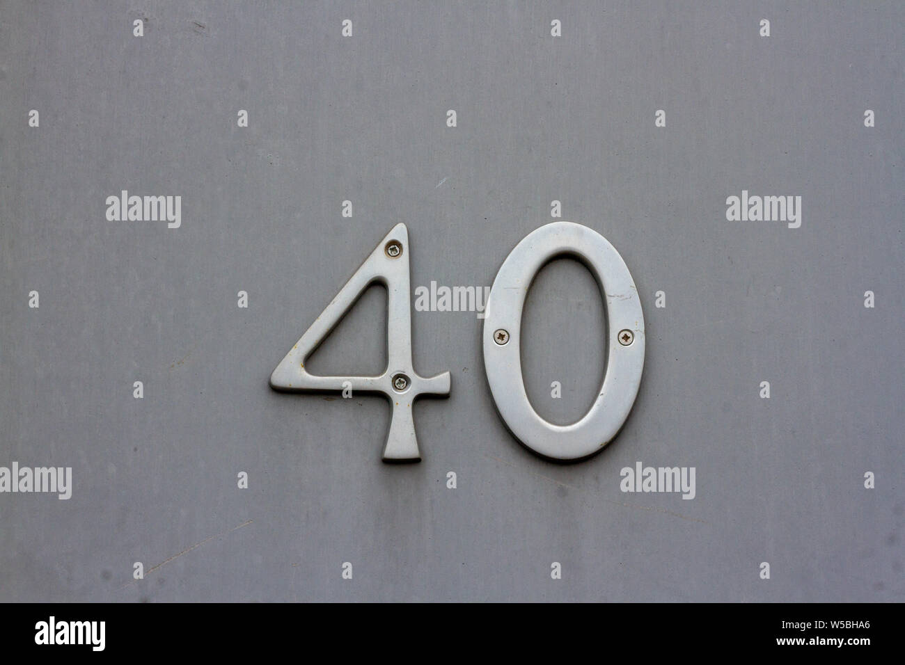 House number 40 with the forty in silver metal digits on a gray wooden ...