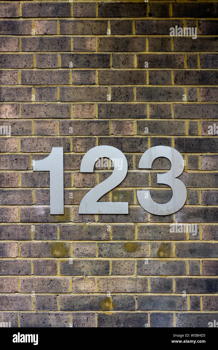 House number 123 on a yellow brick wall Stock Photo - Alamy