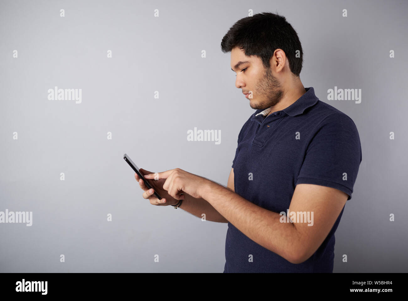 Young man touch smartphone profile view isolated on gray background ...