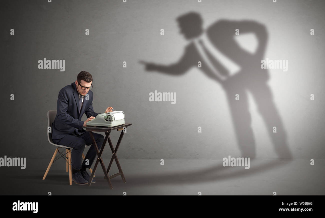 Little man working and a big shadow arguing with him Stock Photo - Alamy