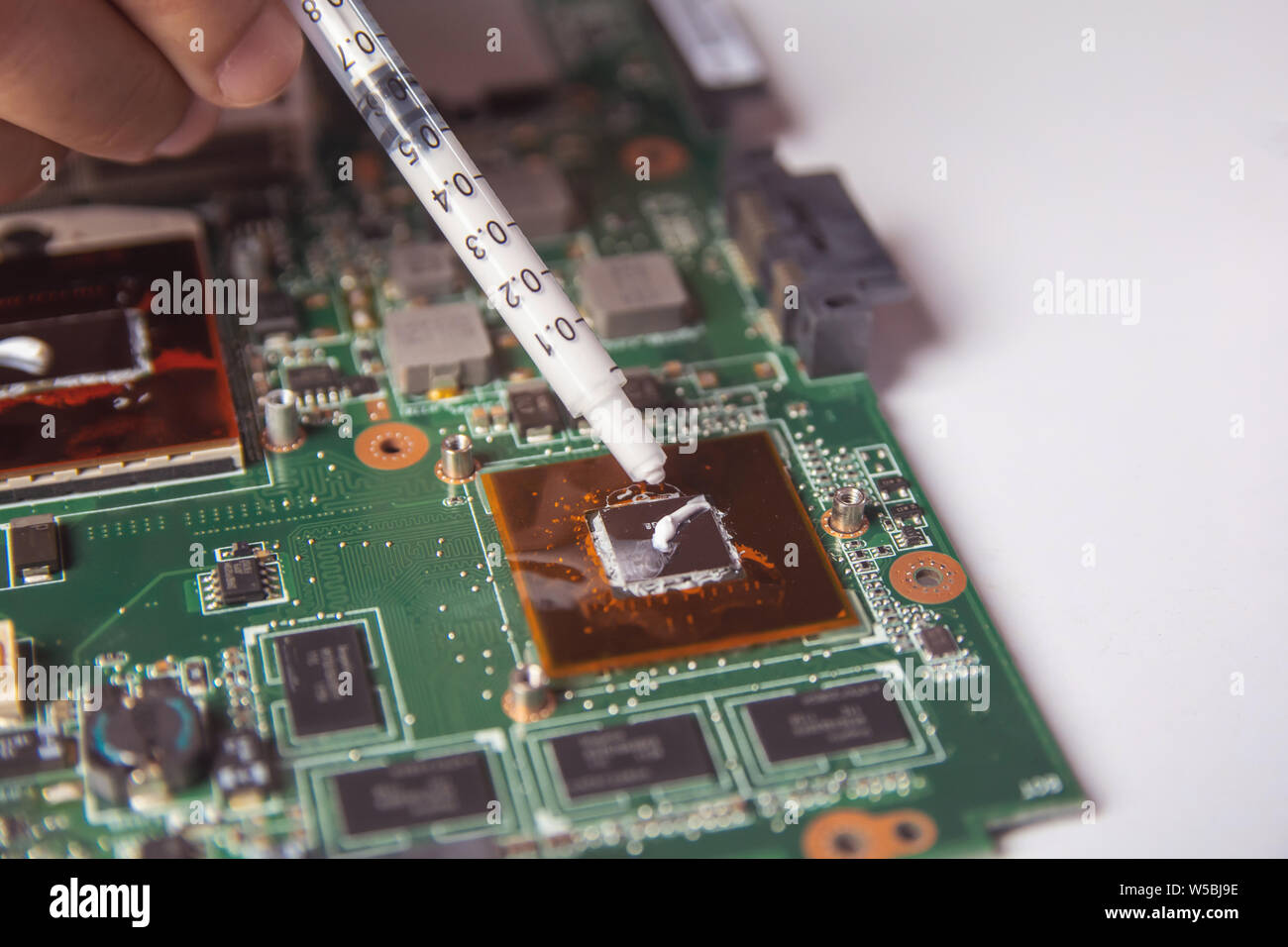 Technician applying thermal paste with syringe on the GPU processor on ...