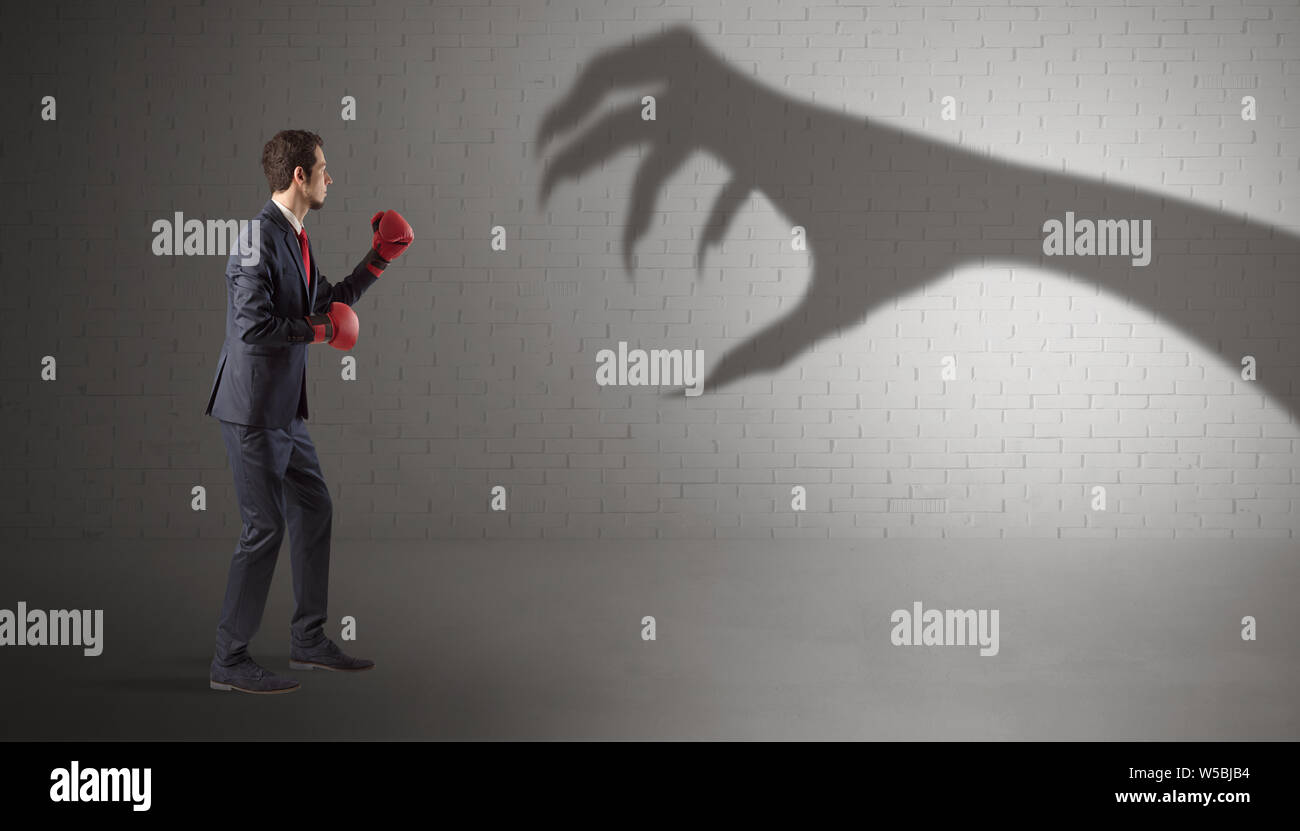 Tiny businessman fighting with scary hand shadow Stock Photo - Alamy