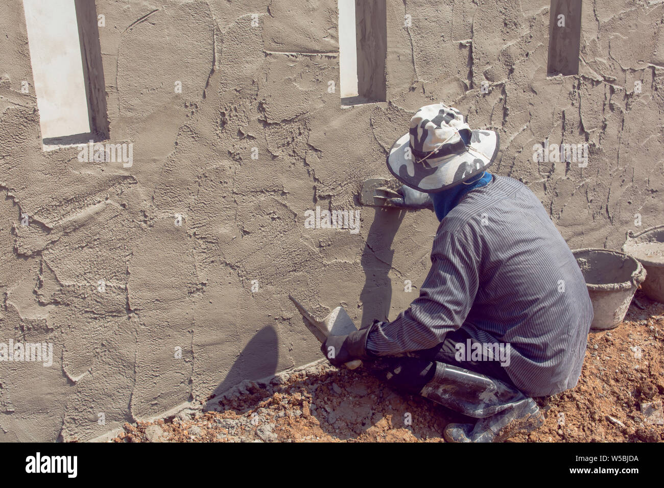 Construction workers plastering building wall using cement plaster ...
