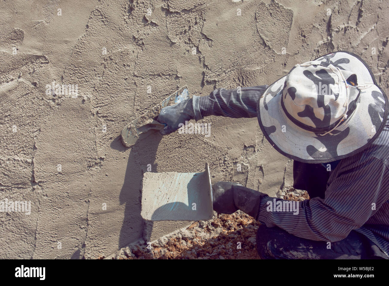 Construction workers plastering building wall using cement plaster ...