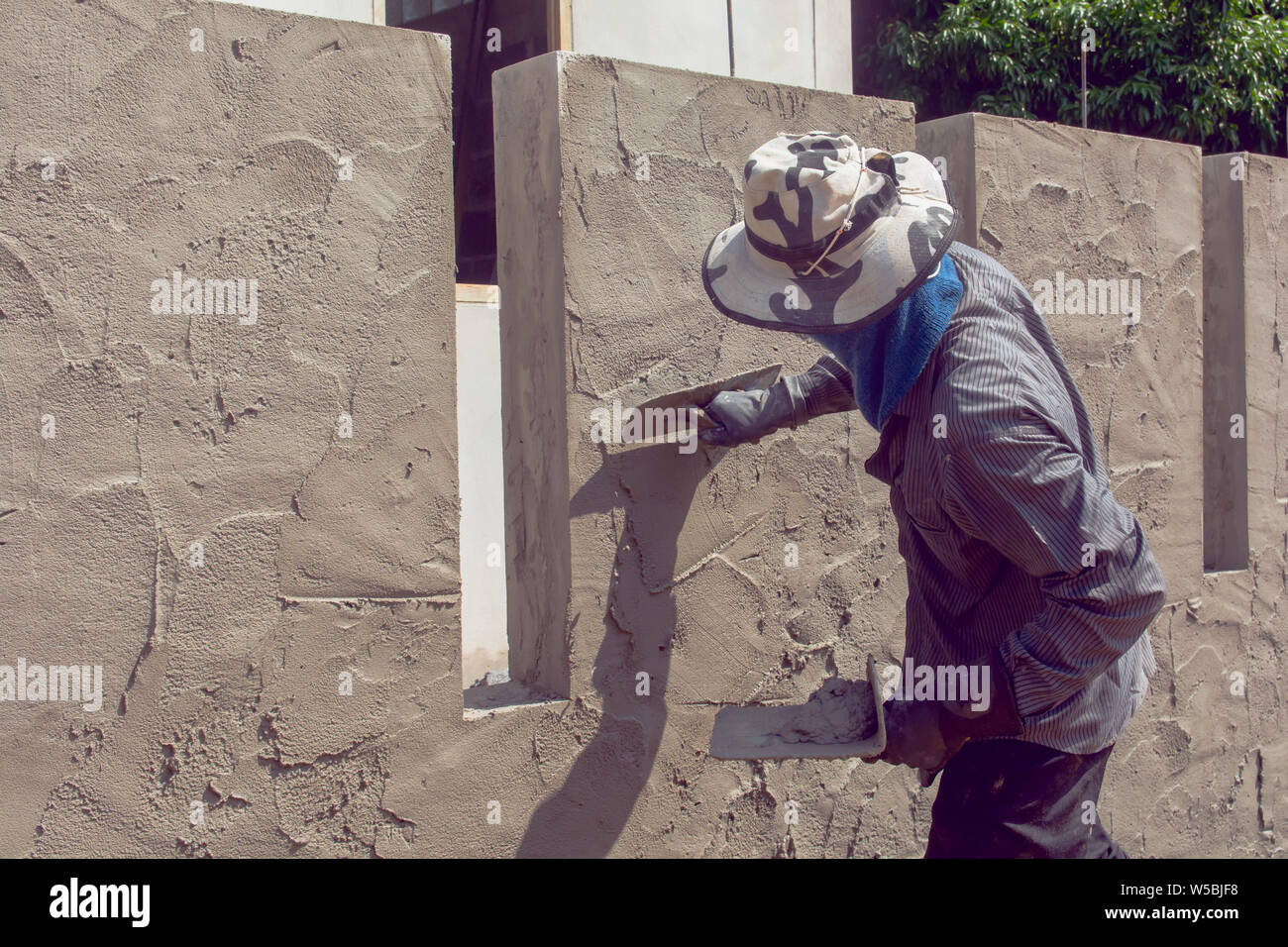 Construction workers plastering building wall using cement plaster ...