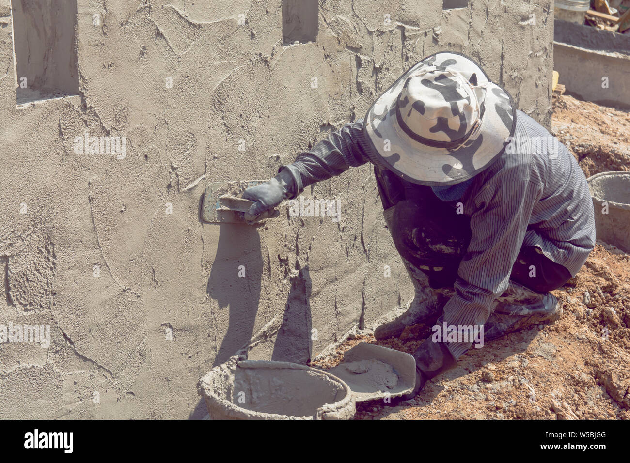 Construction workers plastering building wall using cement plaster ...