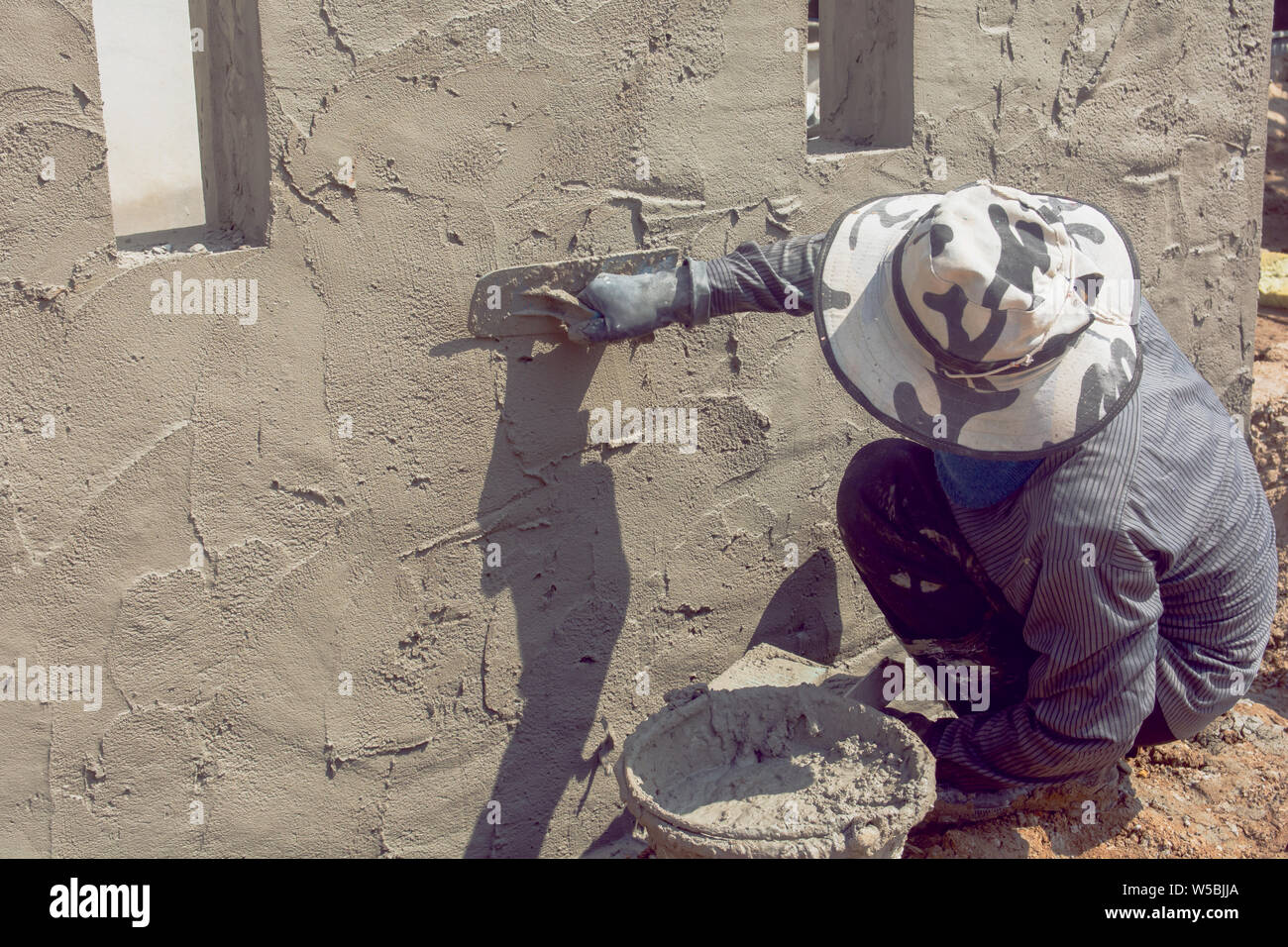 Construction workers plastering building wall using cement plaster ...