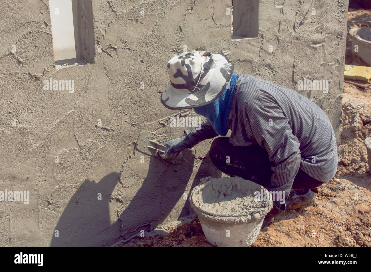 Construction workers plastering building wall using cement plaster ...