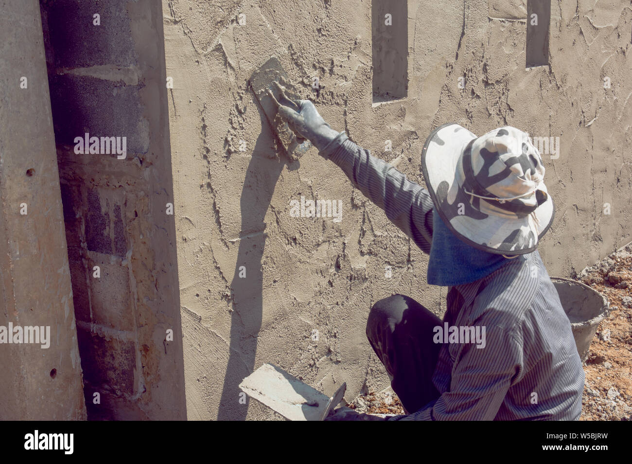 Construction workers plastering building wall using cement plaster ...