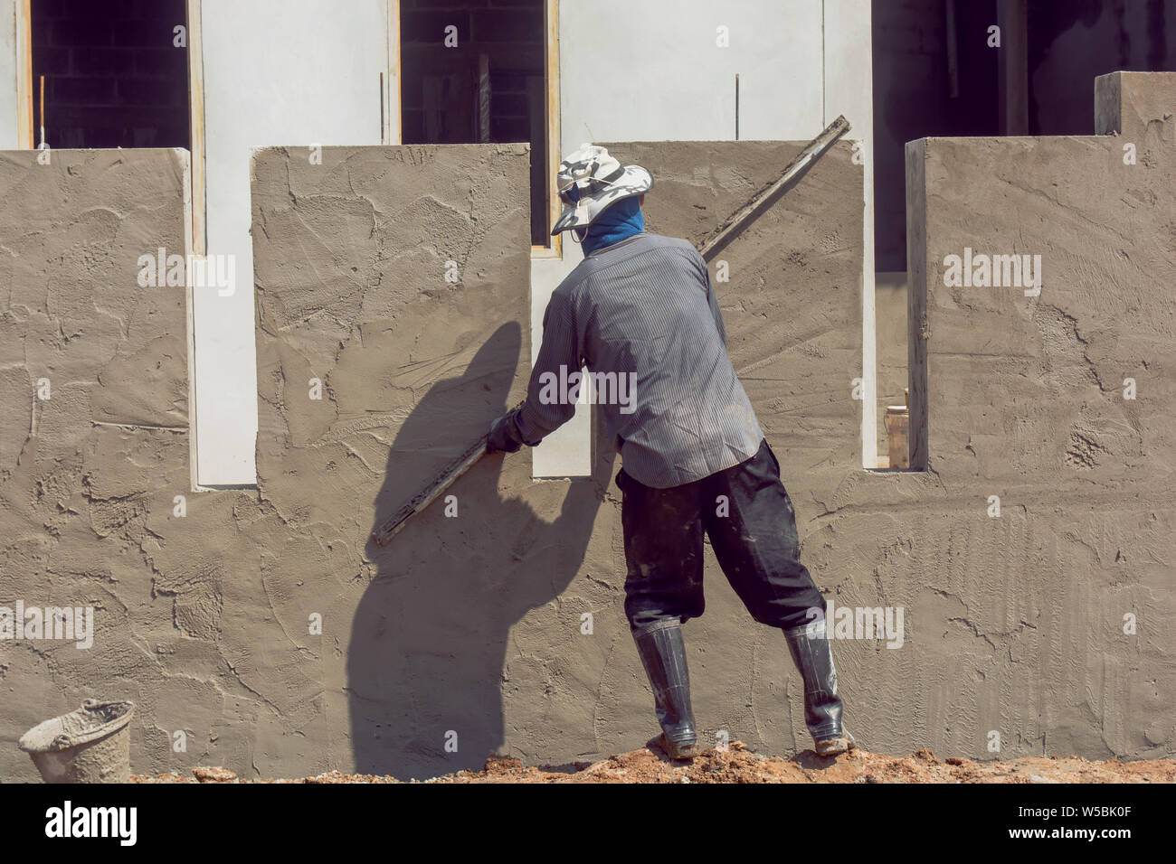 Construction workers plastering building wall using cement plaster ...