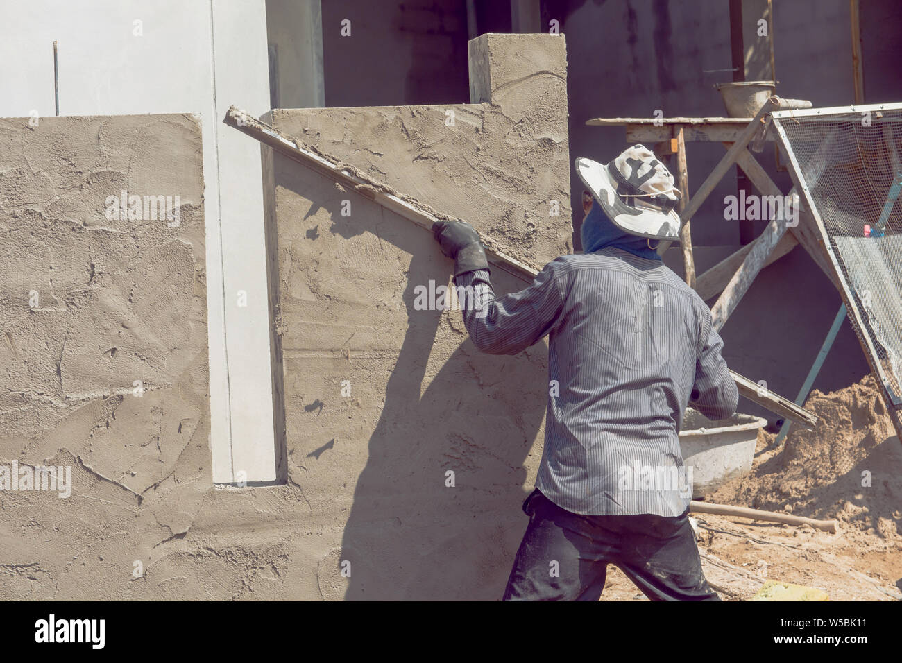 Construction workers plastering building wall using cement plaster ...