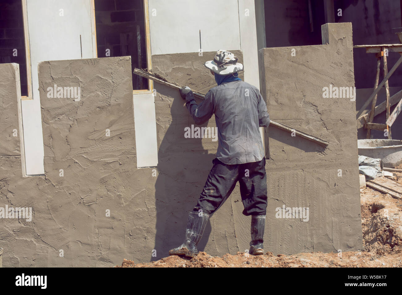 Construction workers plastering building wall using cement plaster ...