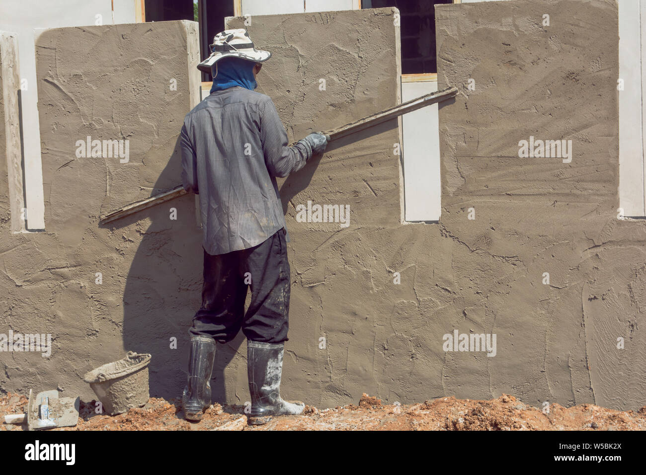Construction workers plastering building wall using cement plaster ...