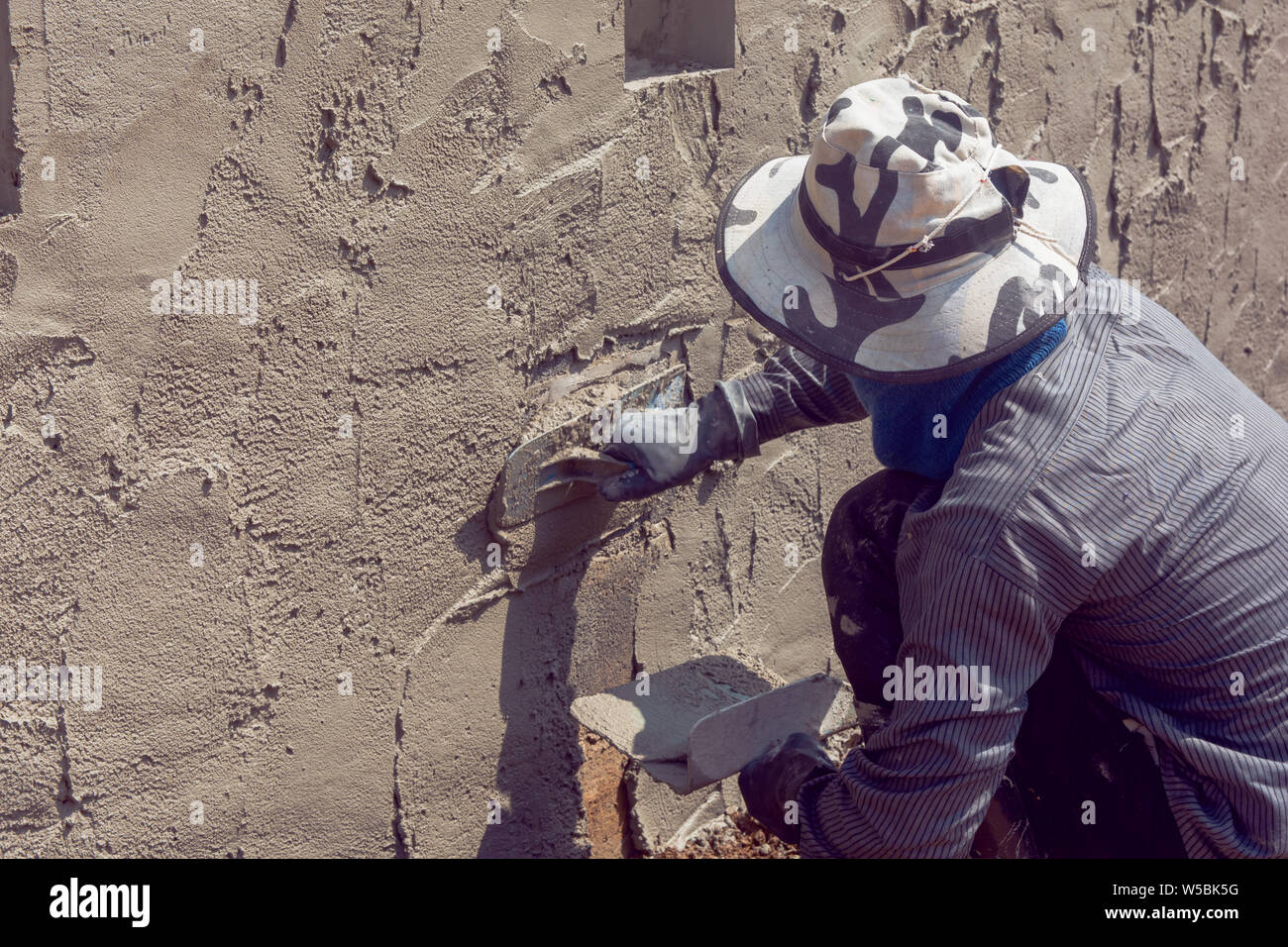 Construction workers plastering building wall using cement plaster ...