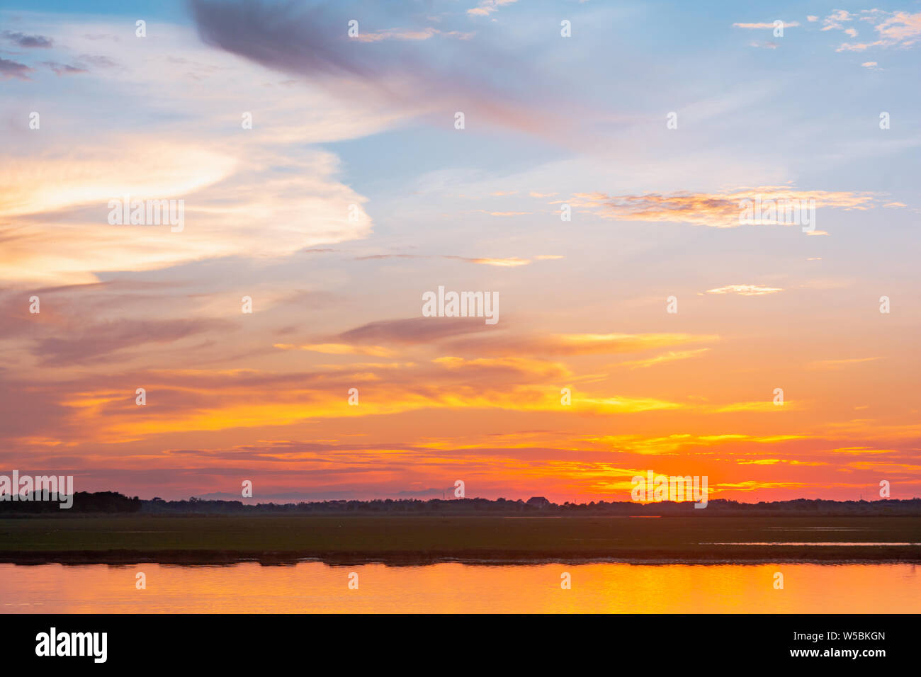 Sunset reflection lagoon. beautiful sunset behind the clouds and blue sky above the over lagoon ...